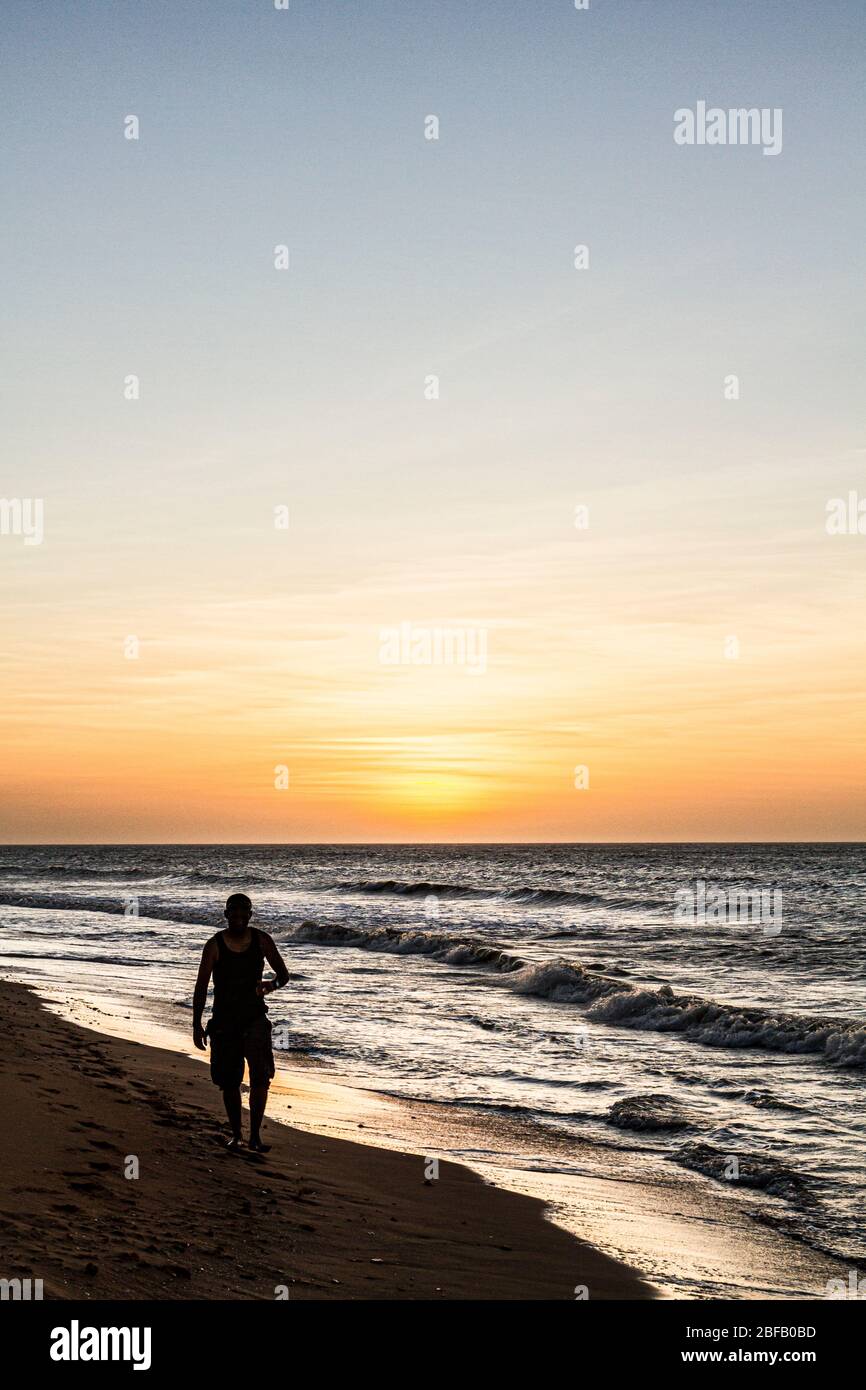 Silhouette of a man walking on Medanos Blancos Beach at sunset, in ...