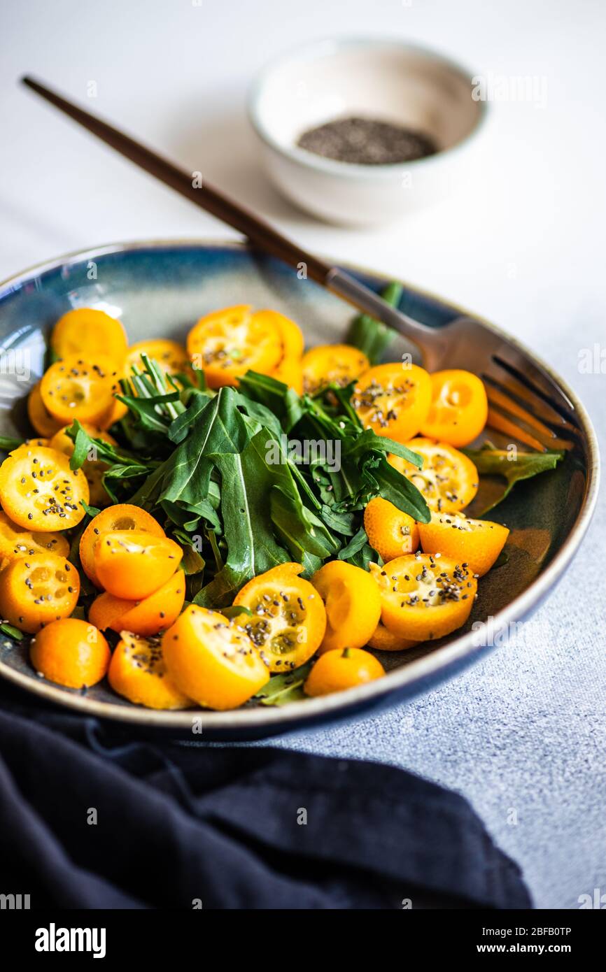 Healthy salad with rocket herb, kumquat fruits and chia seeds on stone ...