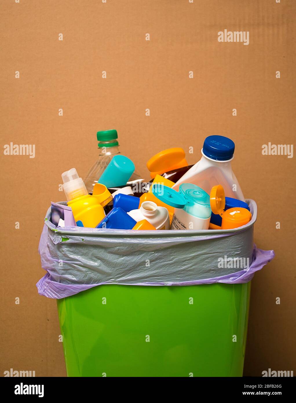 Colorfull plastic waste in the green trash can on brown bacground Stock ...