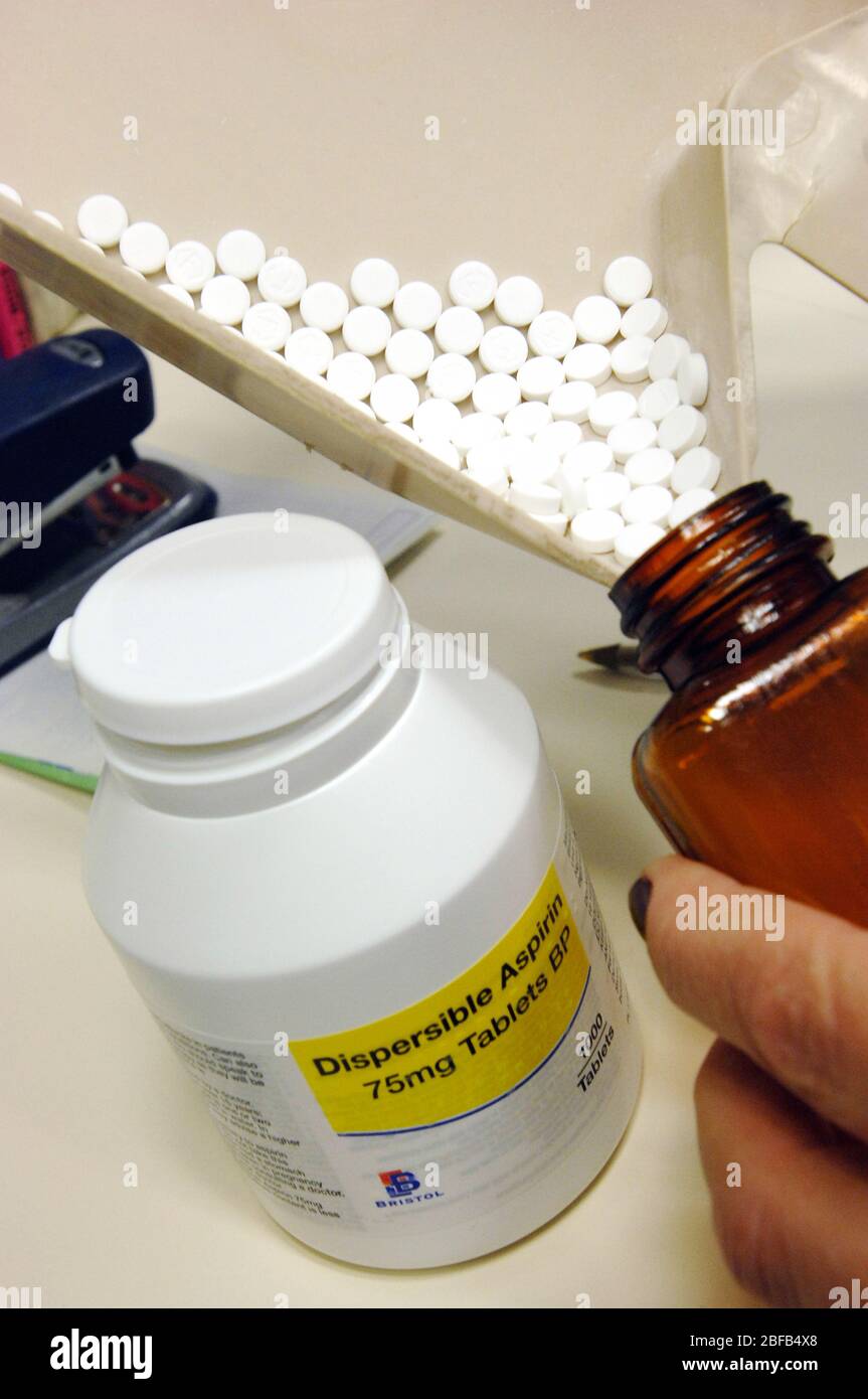 A pharmacist dispenses 75mg tablets of aspirin into a pill bottle Stock ...