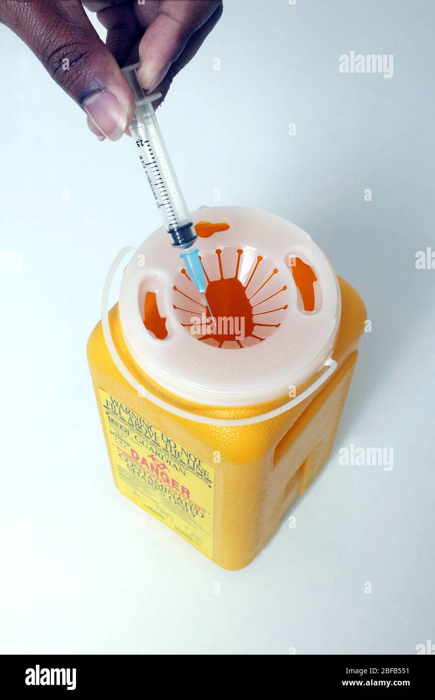 A vet disposes of a used syringe into a sharps bin Stock Photo - Alamy