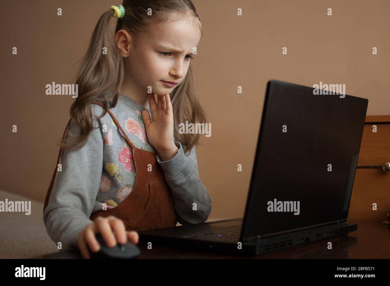 Shocked sad tired little girl is trying to do her complicated homework ...