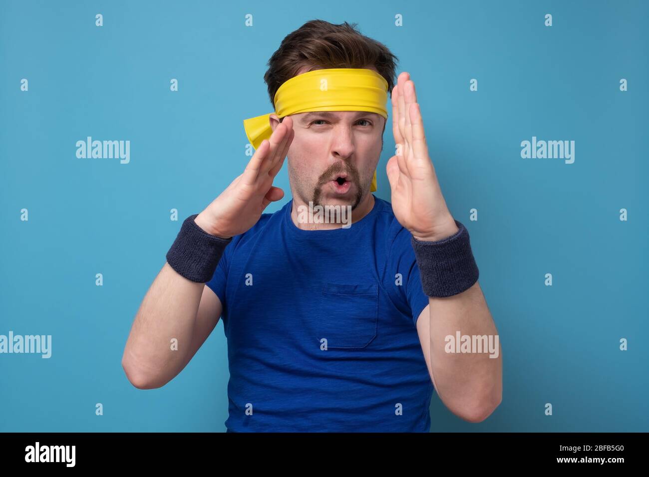 Attractive and serious adult man with mustache shows karate chop ...