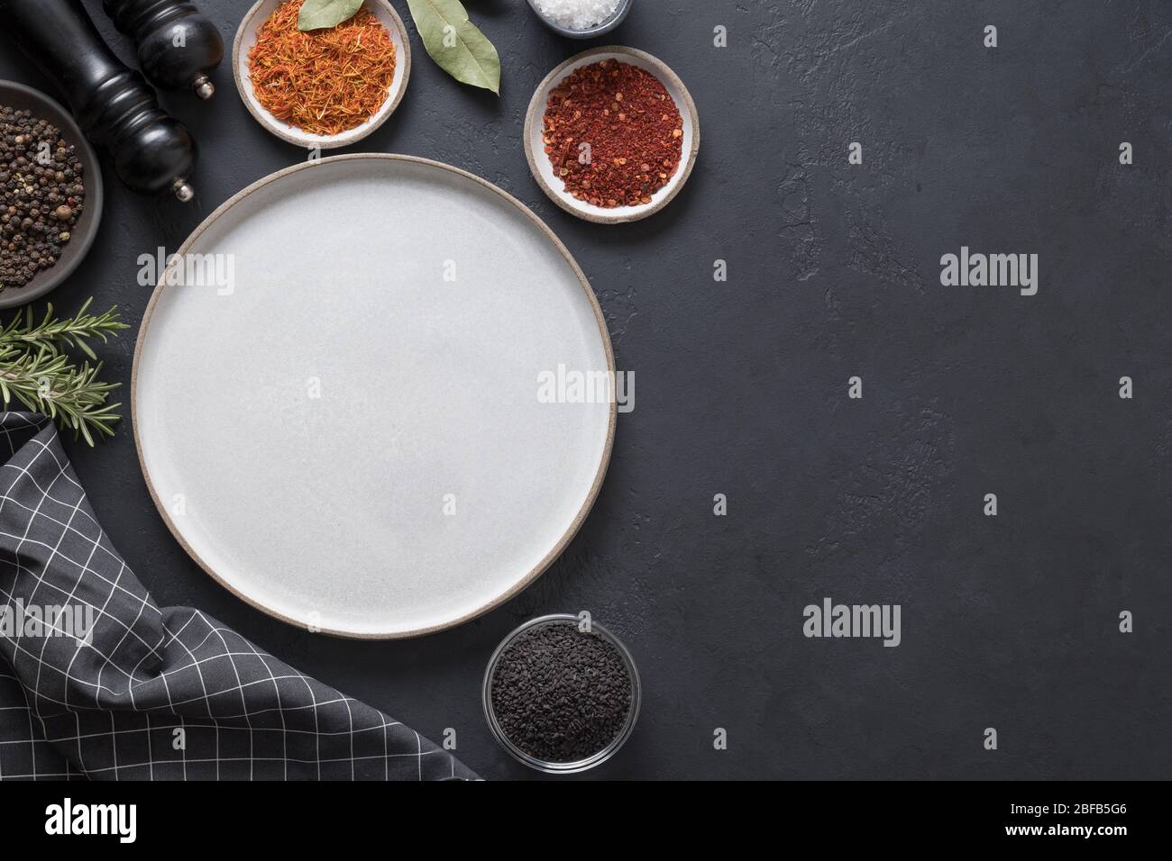 Gray platter and spices for cooking and marinade on black. Space for ...
