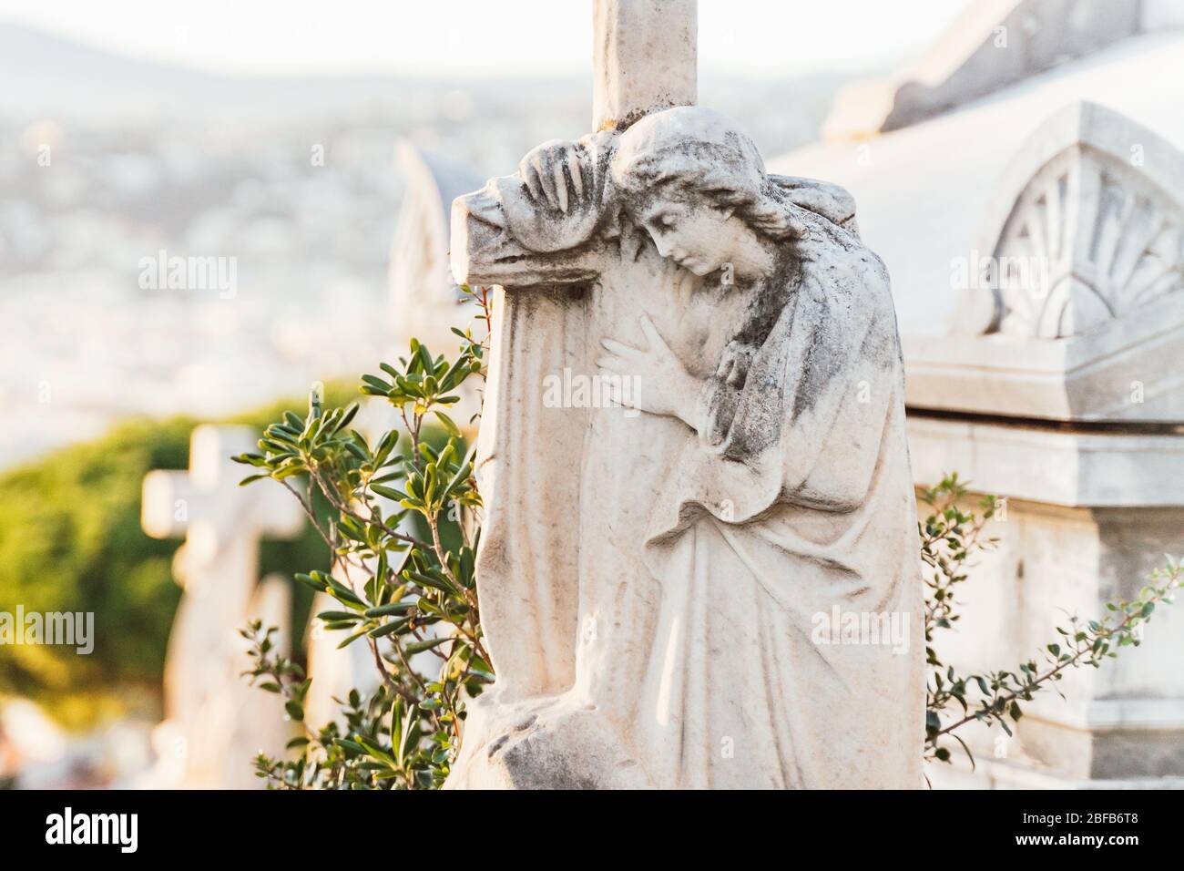 sculpture of a angel with a cross at old cemetery. Closeup of stoned ...