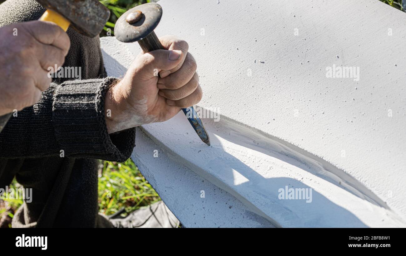 Closeup of an artist carving precise curves in white stone, using ...