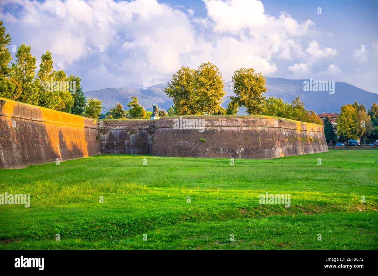 Defensive brick city wall, grass green lawn, trees and Tuscany hills ...