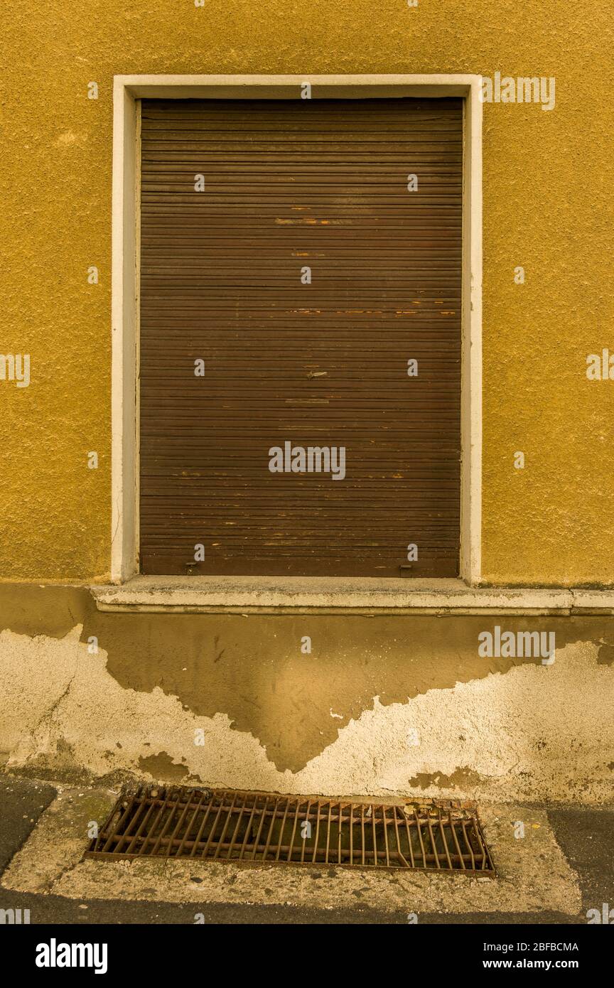 old facade with brown wooden shutters and shaft for basement windows ...