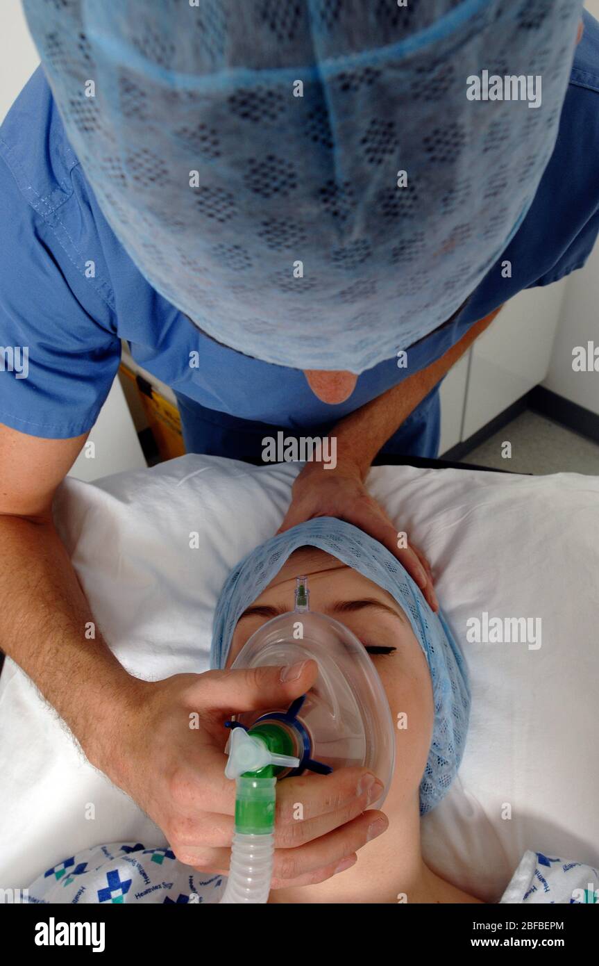 An anaesthetist administering medical gases to put a patient to sleep ...