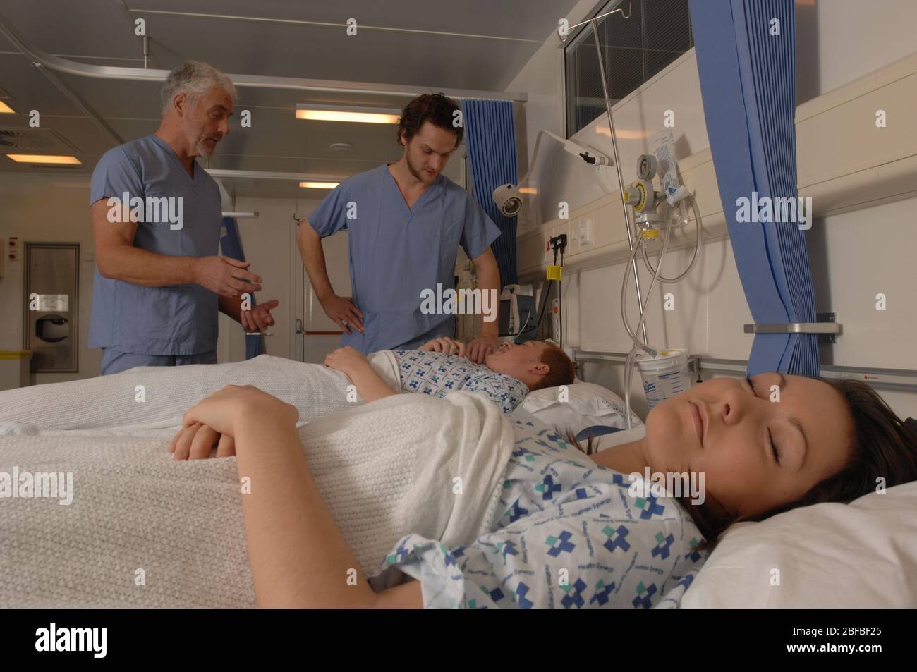 A surgeon (left) and a member of his surgical team talk with patients ...