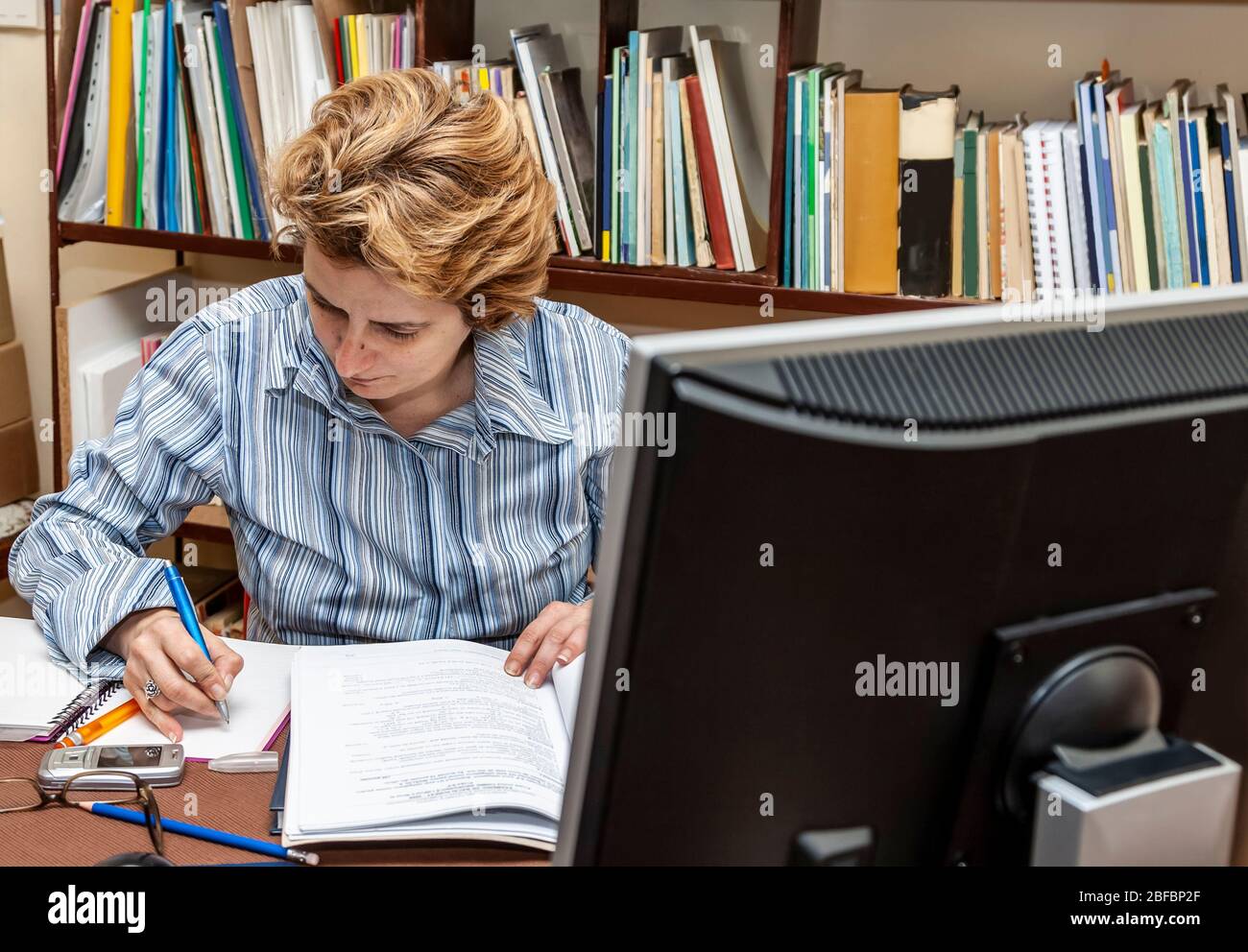 Image of a busy woman teleworking at her desk at the home. Working at ...