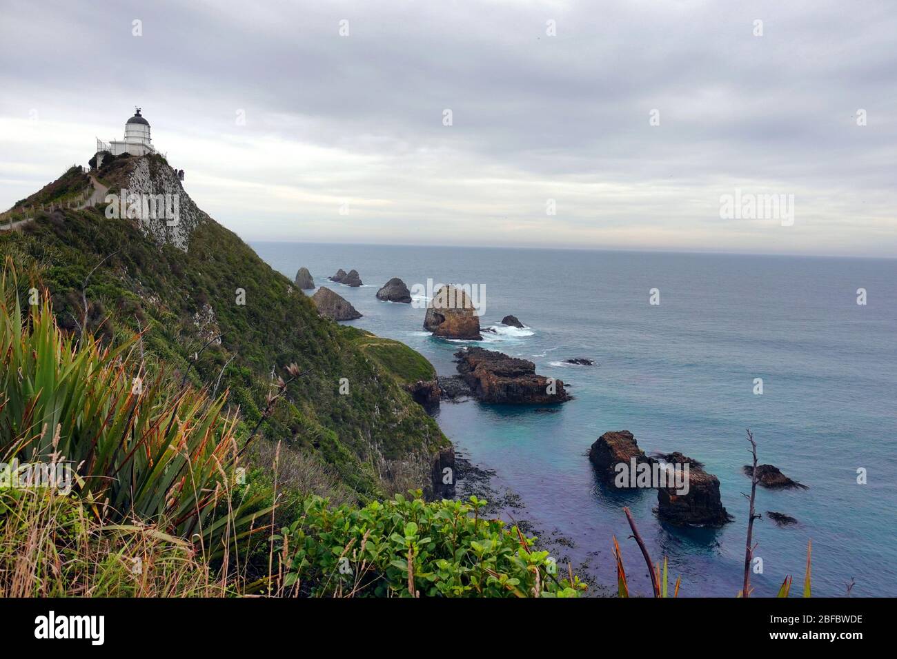 The Nugget Point Lighthouse at a stormy day with the cliff and boulders ...