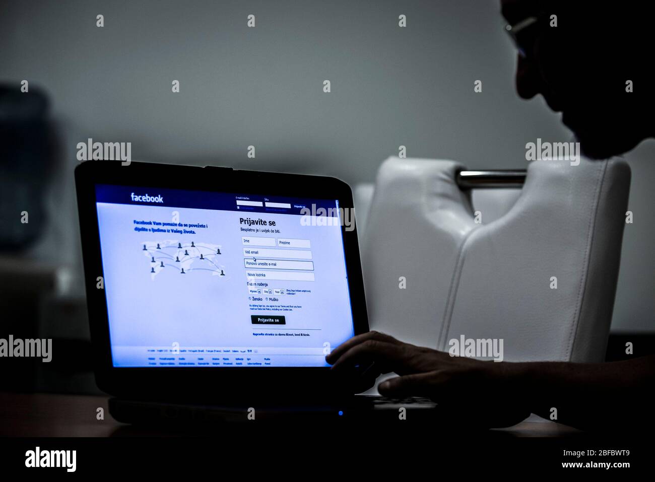 Man uses computer to og in and check social network Facebook Stock ...