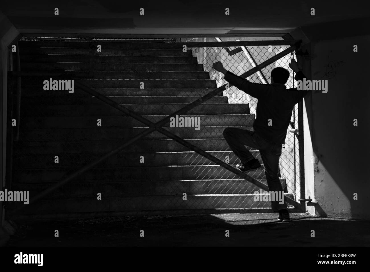 Man silhouette desperately trying to escape from the locked metal woven ...