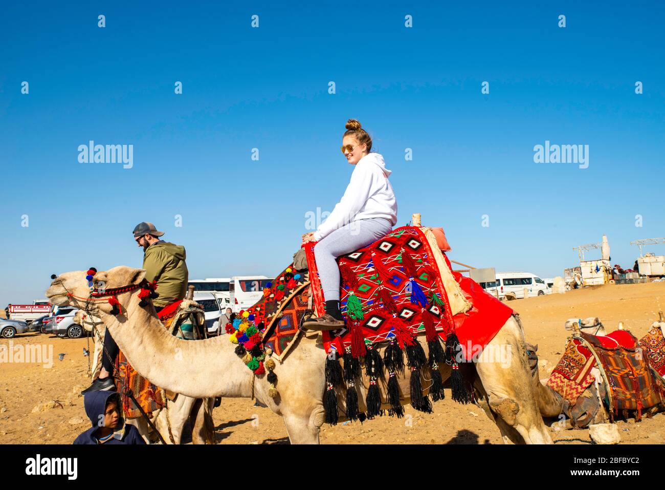 A teenage girl prepares to ride a camel at the Giza Pyramid Complex ...