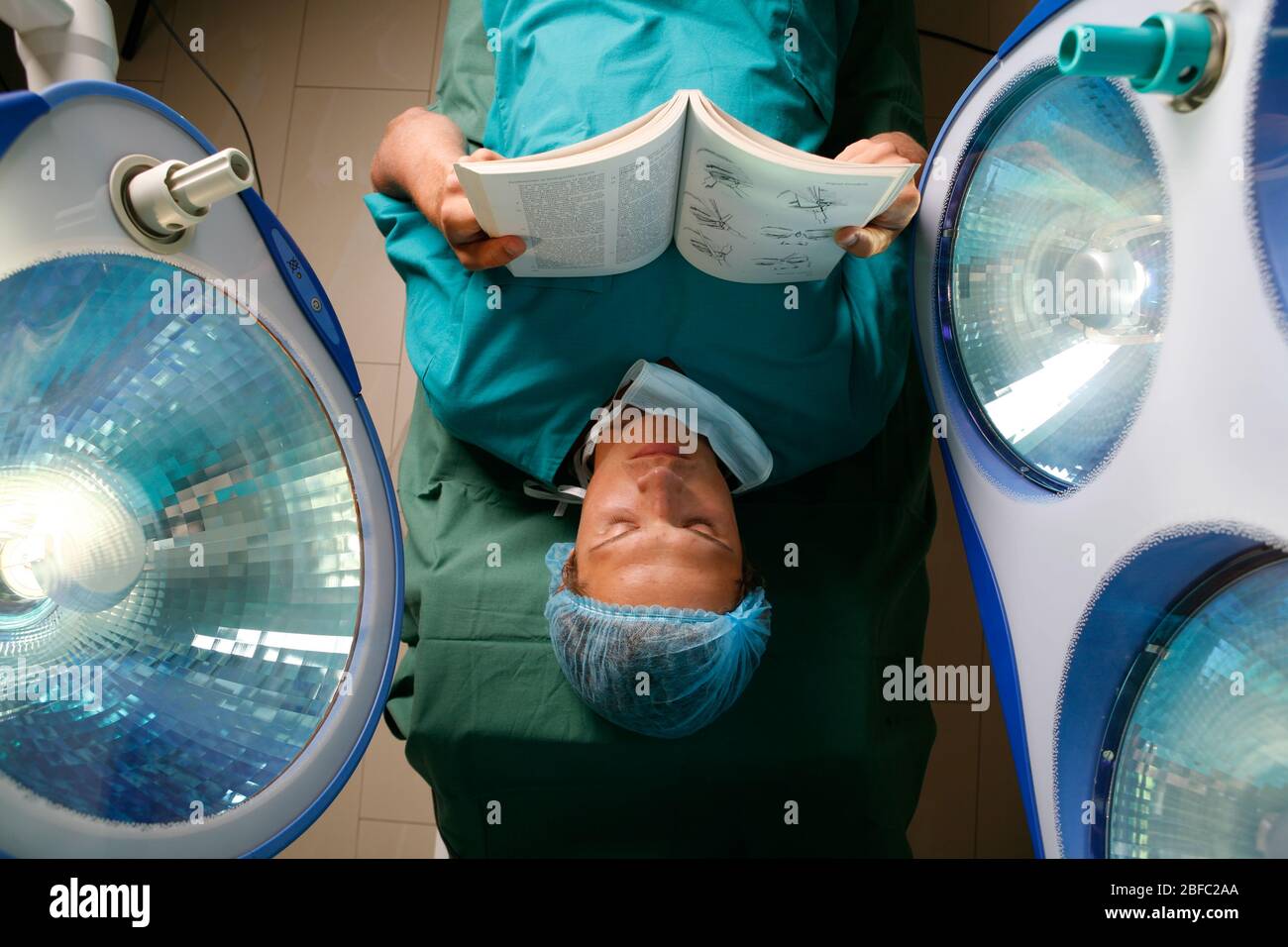 Surgeon laying on an operating table whilst reading a book Stock Photo ...