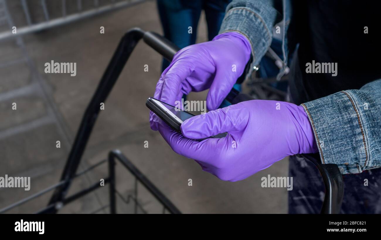 Texting using a mobile phone while on a shopping line to get into store ...