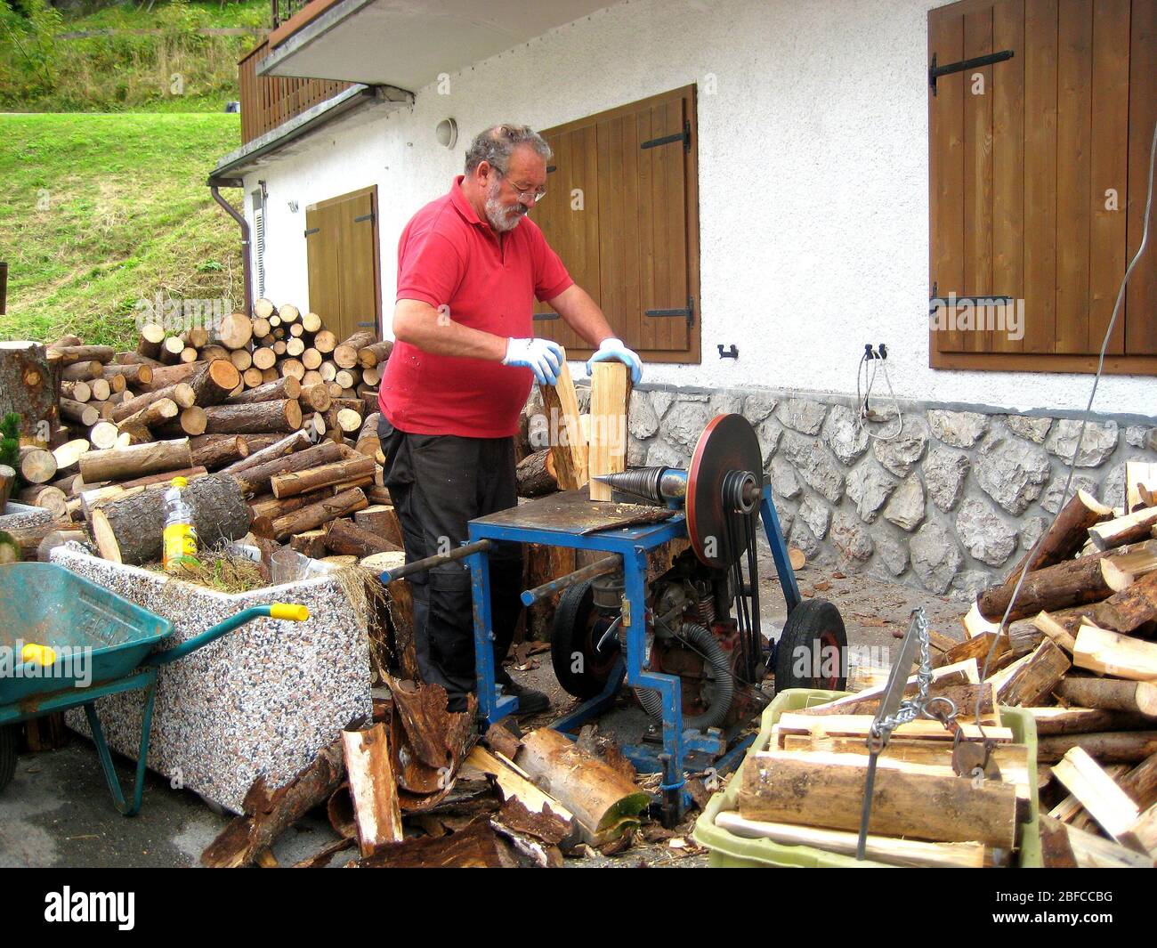 Man splitting wood in summer outside a house in Cortina d'Ampezzo ...