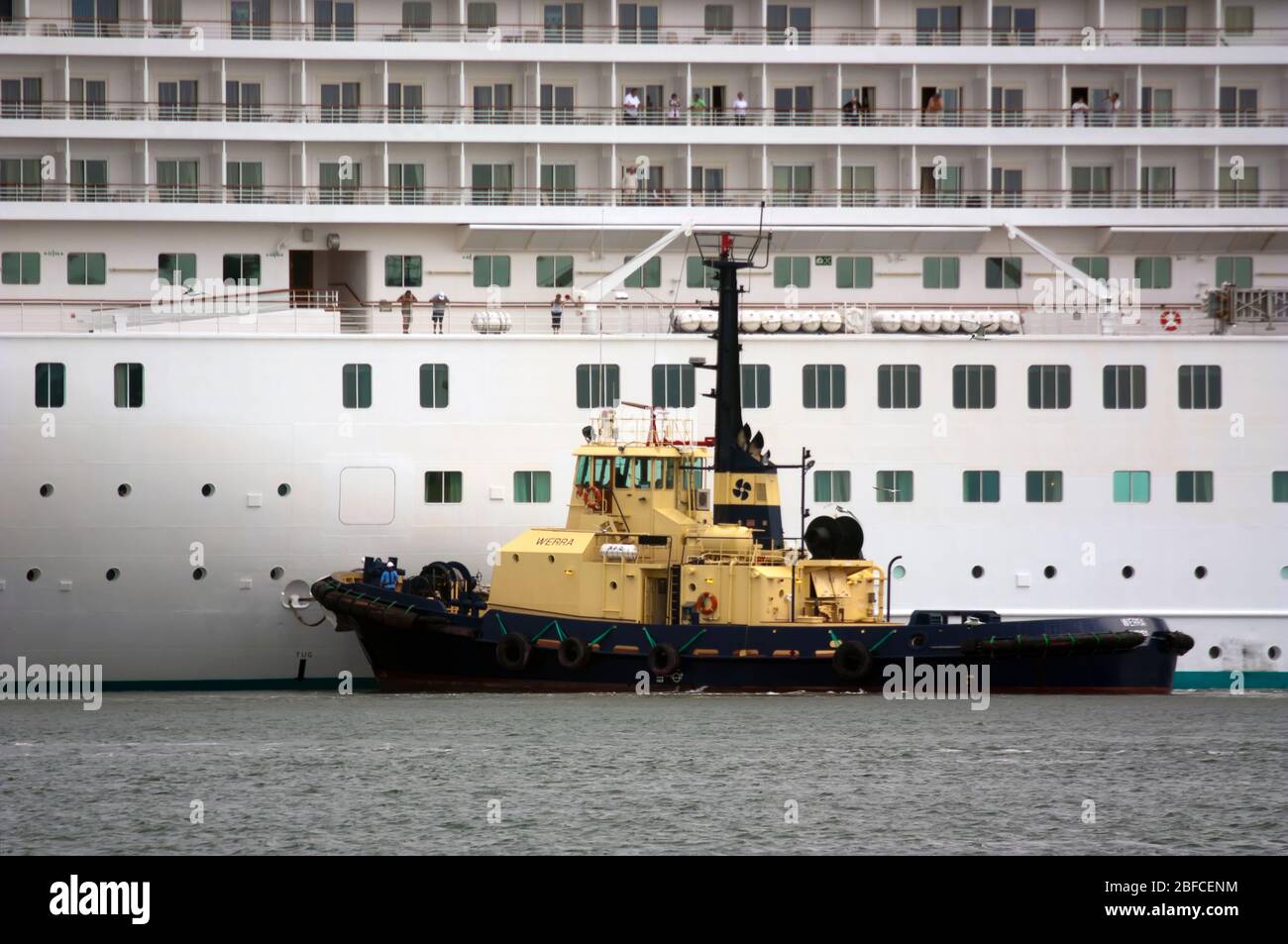 Harbour Tug boat alongside docked cruise ship preparing to set sail ...