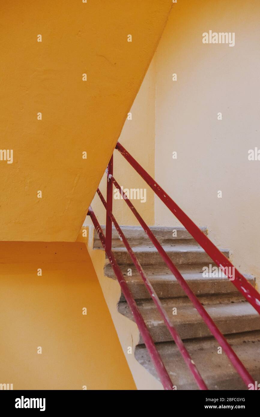 A staircase with red railing is surrounded by yellow walls Stock Photo ...