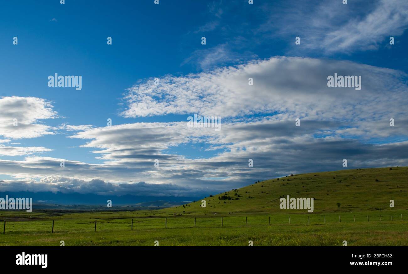 open spacious blue sky with fluffy clouds behind green rolling hills of ...