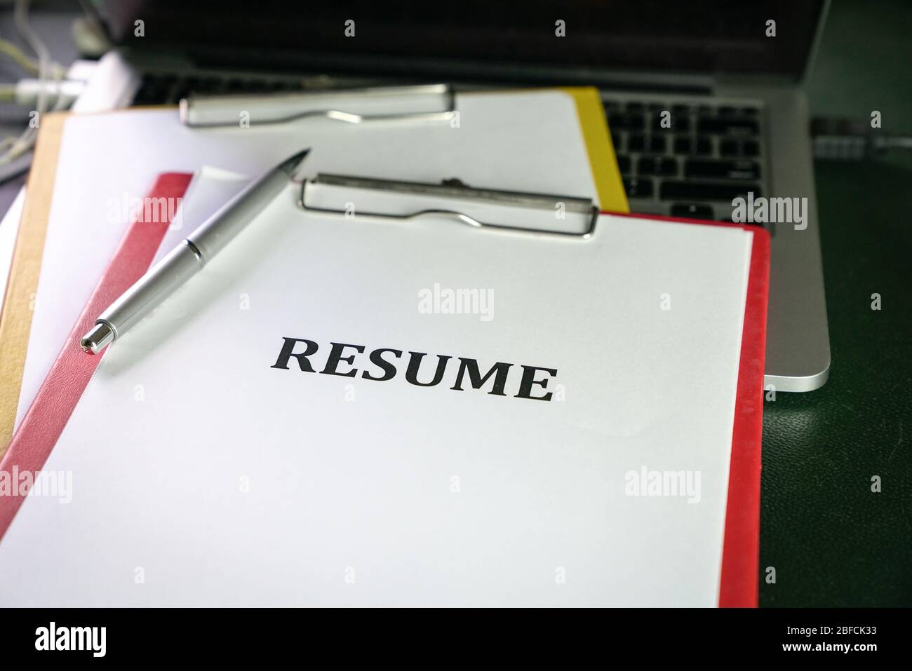 Closeup of resume on top of computer laptop on table with pen Stock ...