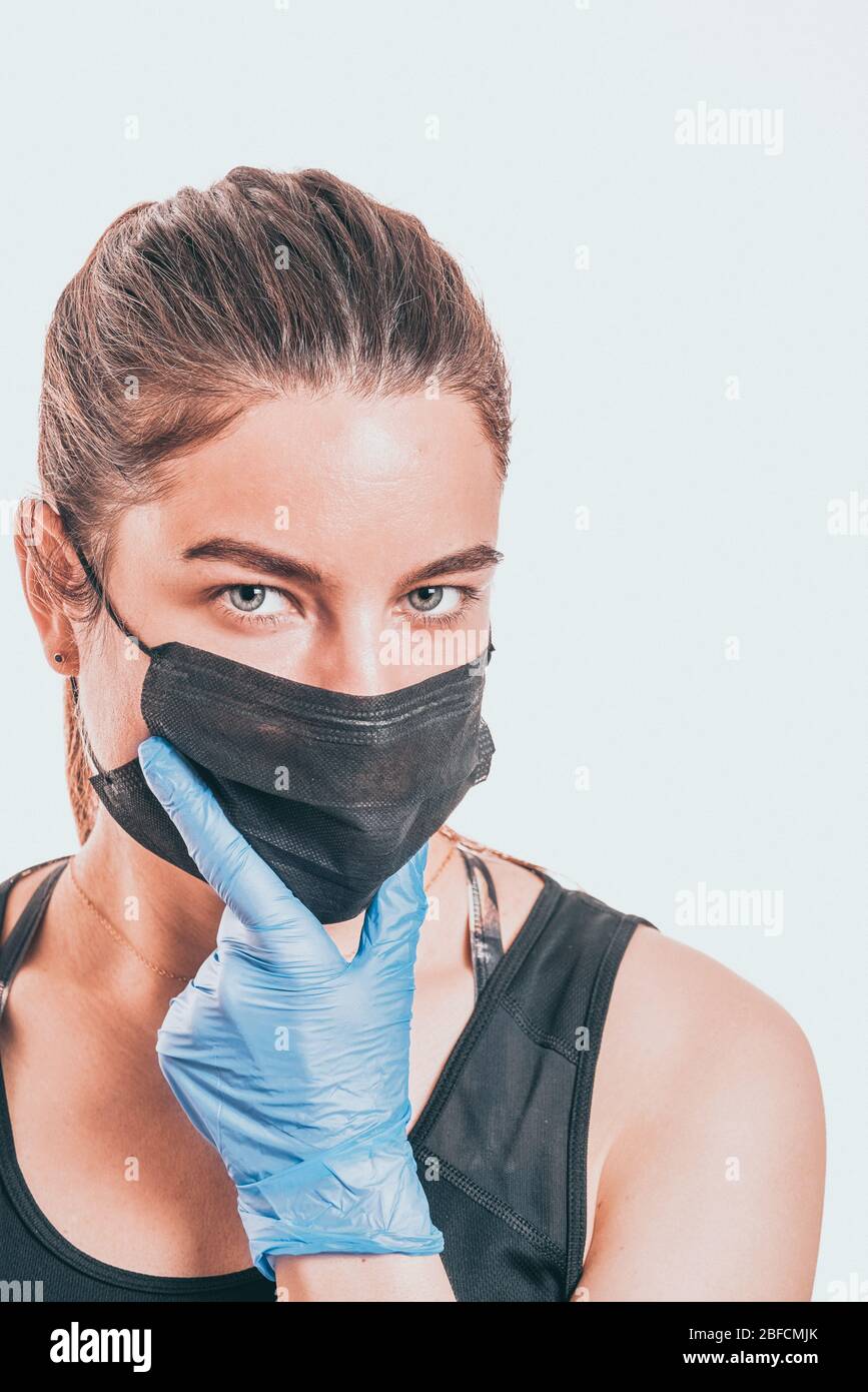 A close-up portrait of a pretty female wearing a surgical mask isolated ...