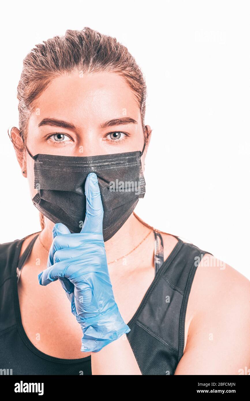A close-up portrait of a pretty female wearing a surgical mask isolated ...