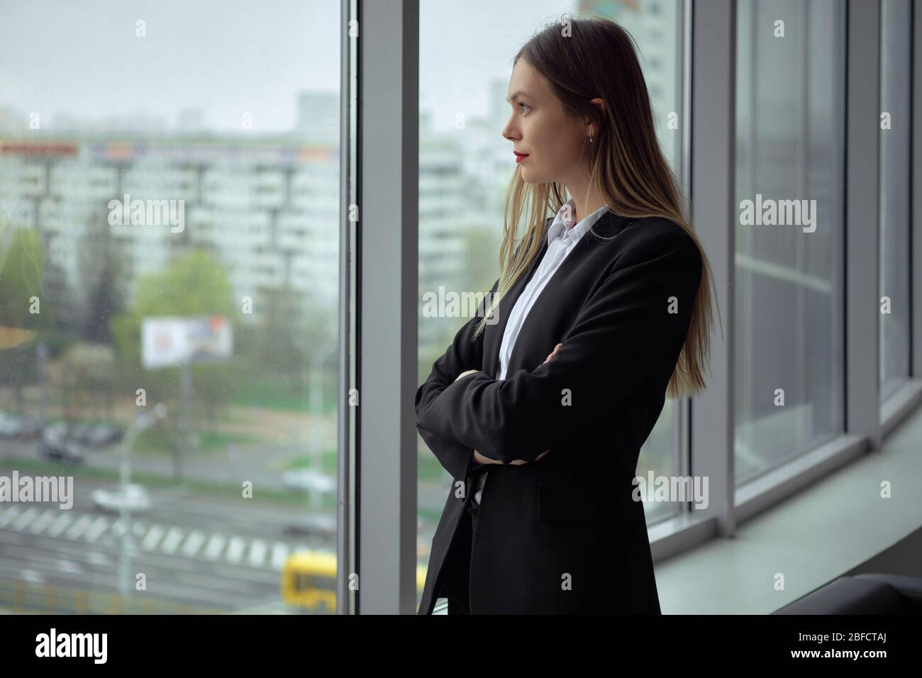 Pretty employee of a construction company looking through the window of ...