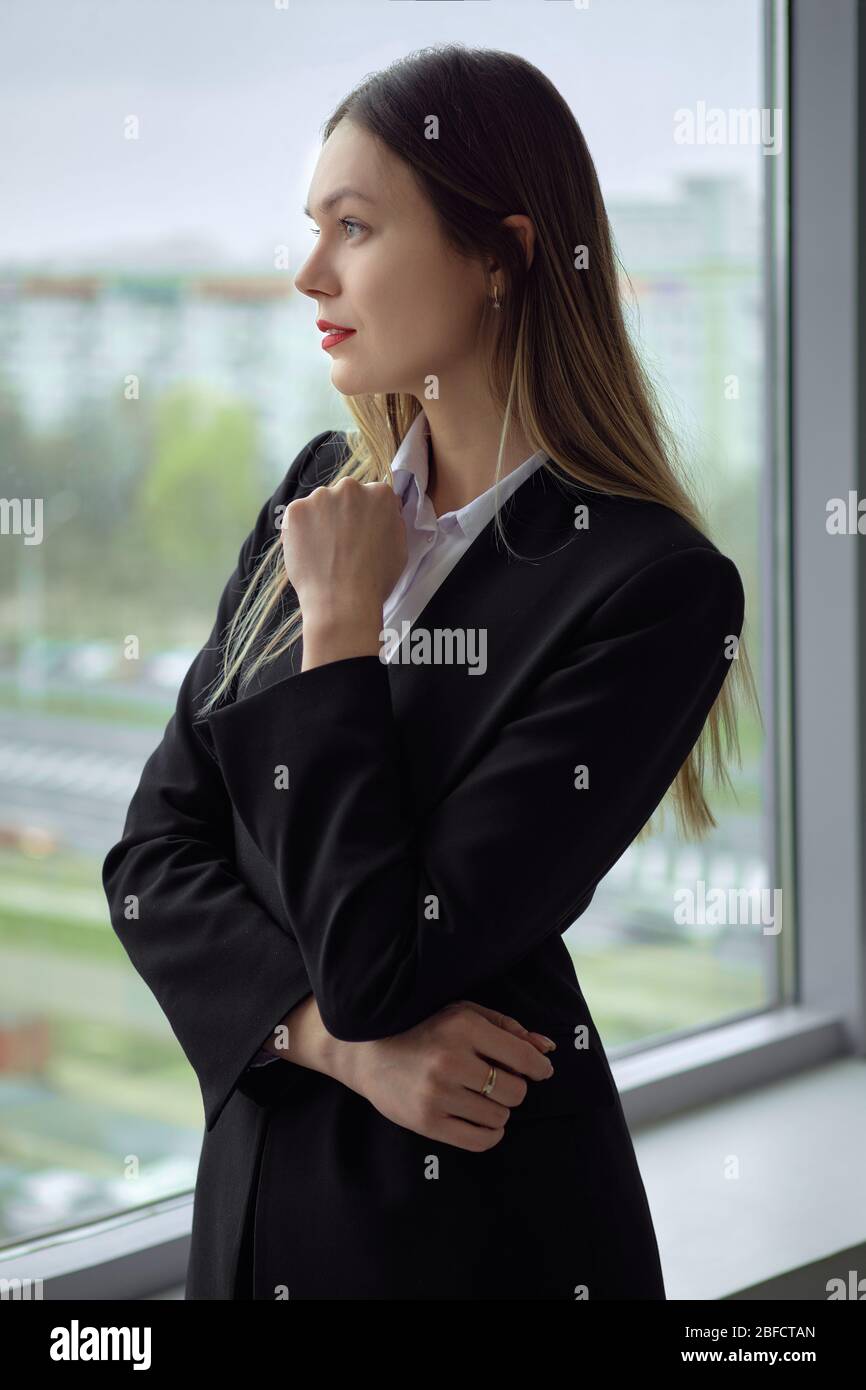 Portrait of modern business woman looking through office window Stock ...