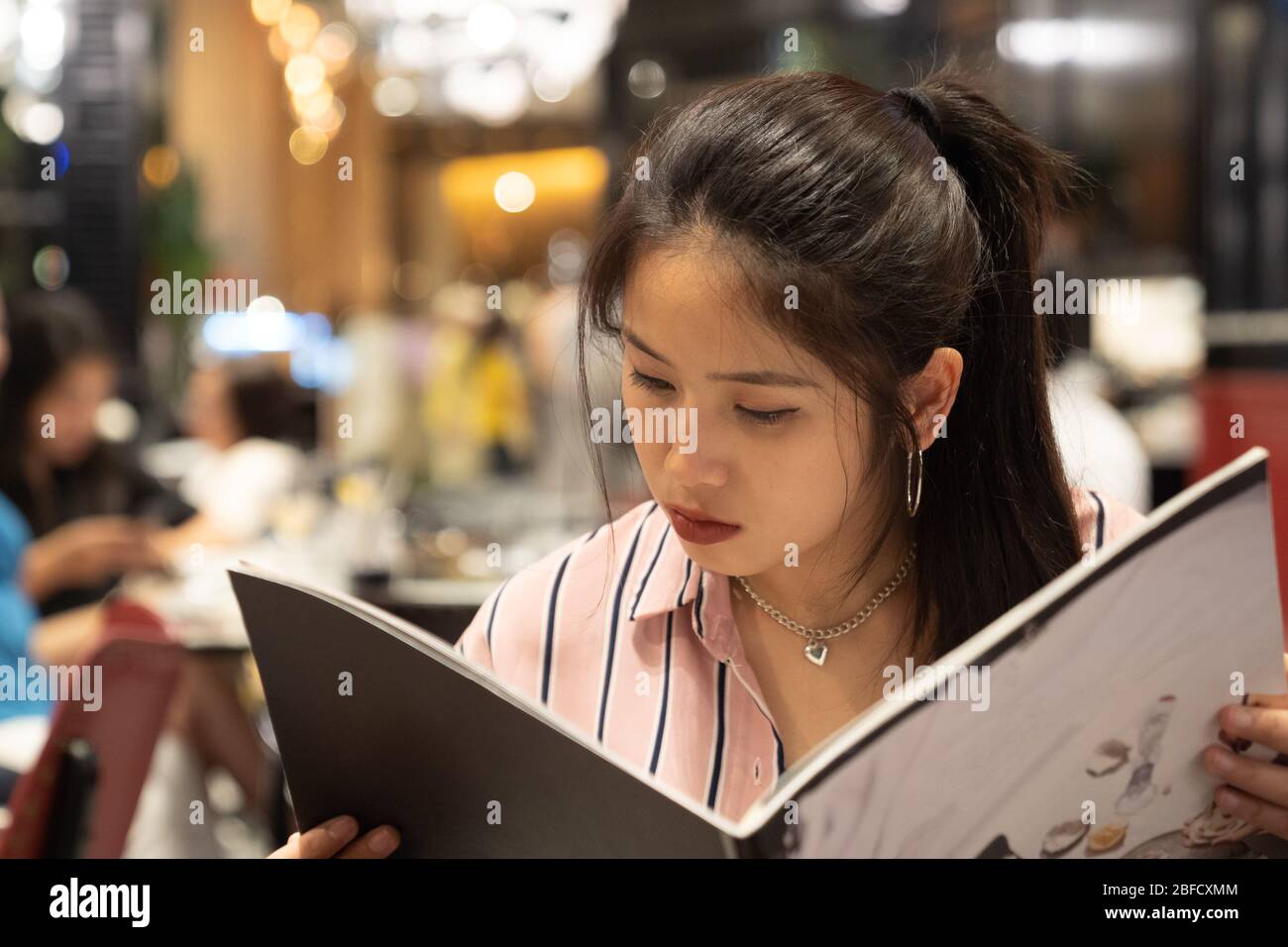 Asian Beautiful woman ordering from menu in luxury restaurant Stock ...