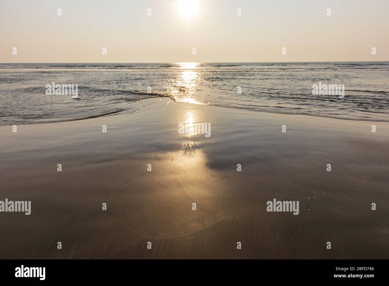 Sunset on Mandrem beach in Goa, India. Sea ebb and exposed bottom in ...