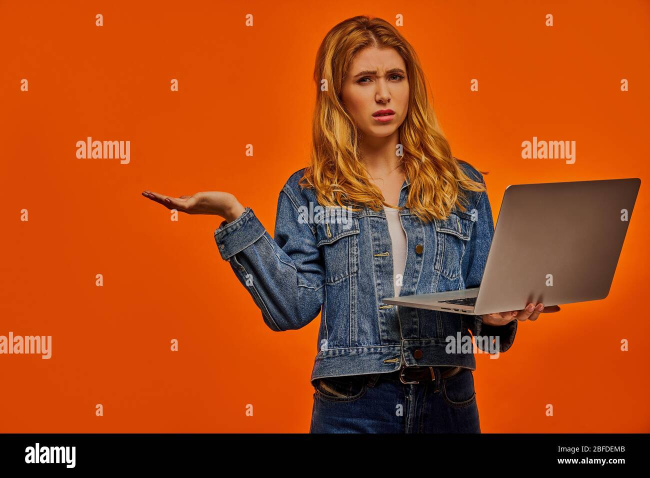 A puzzled woman stands with a laptop in her hand Stock Photo - Alamy