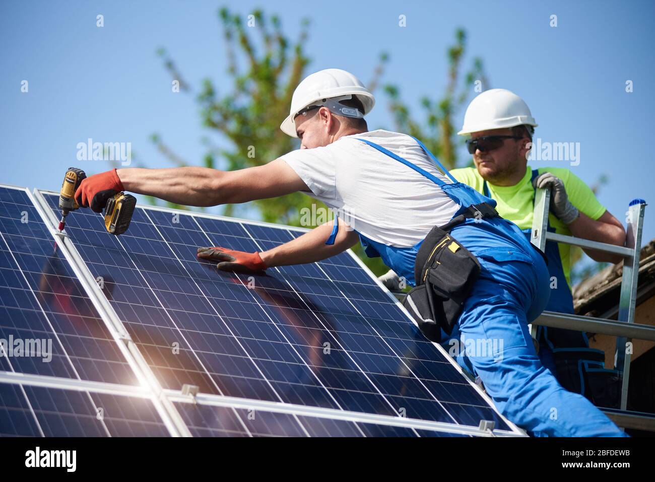 Two workers technicians connecting heavy solar photo voltaic panels to ...