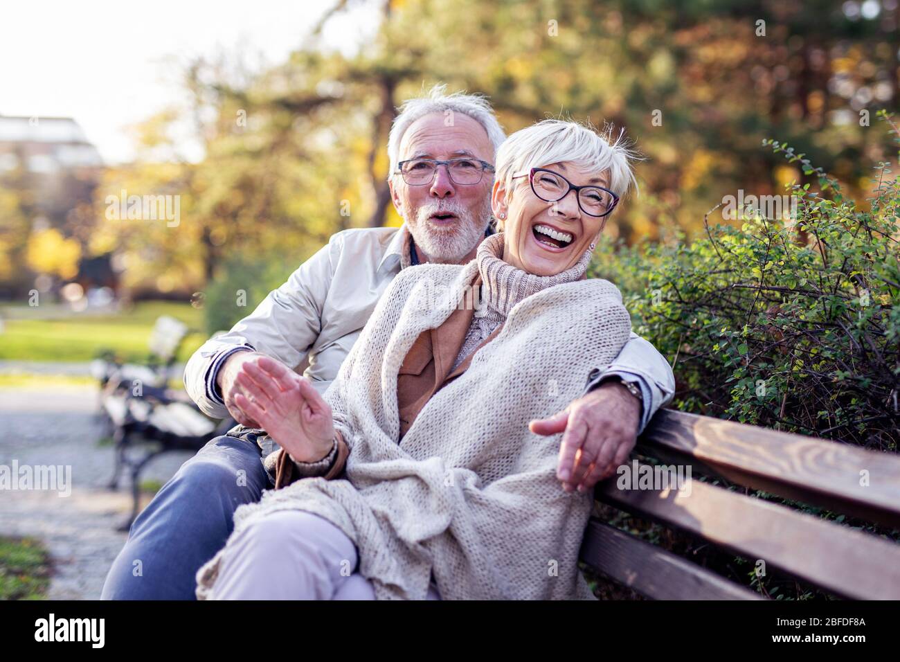Old man and woman sitting on bench and smile Stock Photo - Alamy