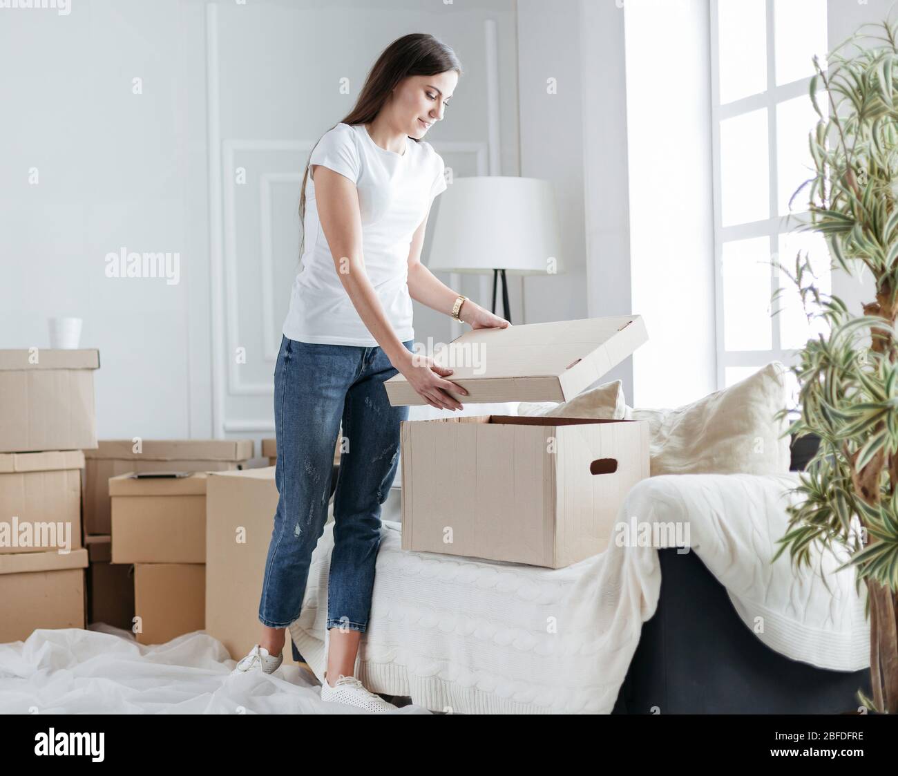 young woman opening a box in a new apartment Stock Photo - Alamy