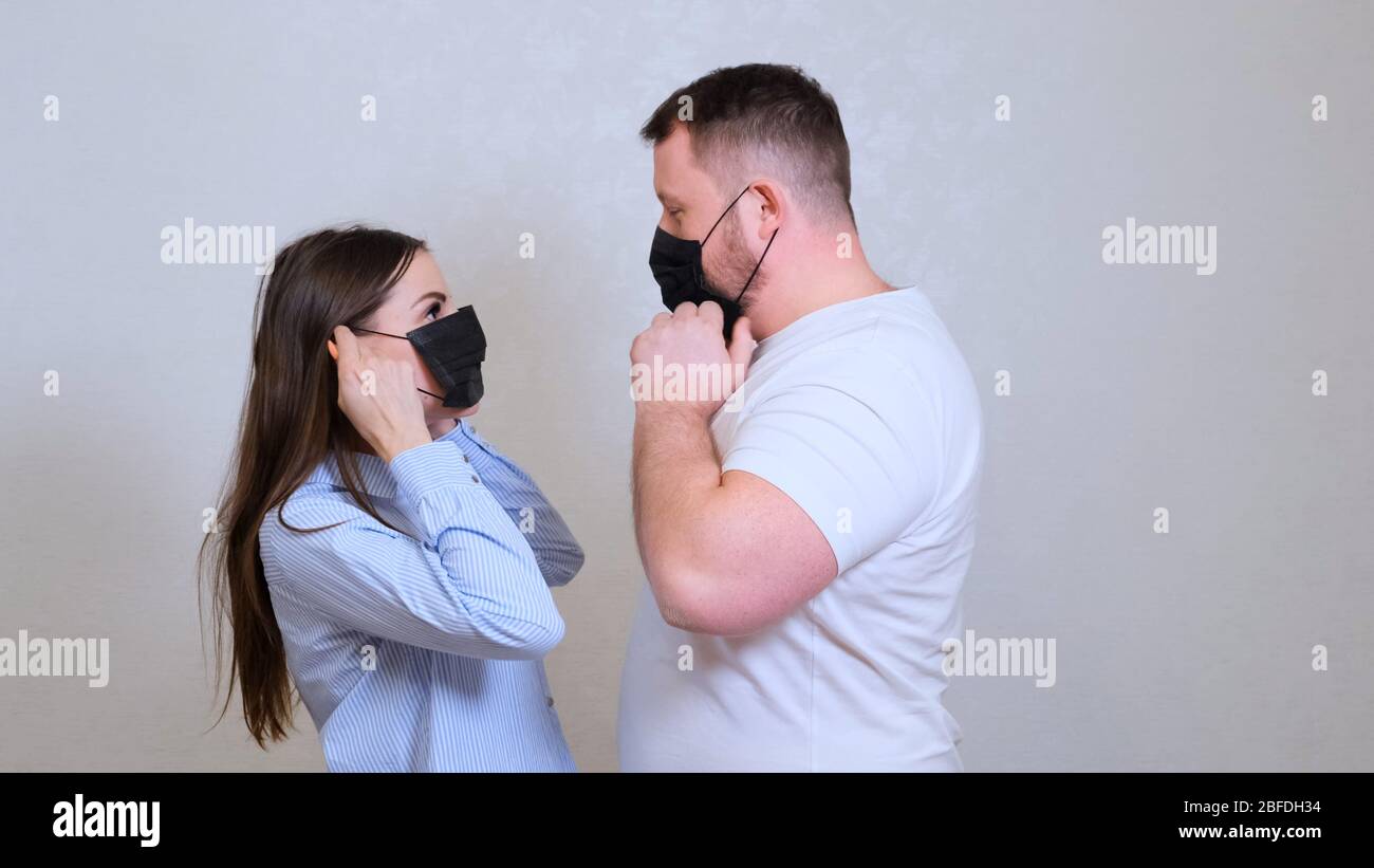 female and male look at each other in protective masks and hug. Hygiene ...