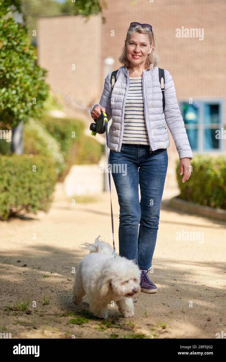 Middle-aged woman walking with dog in summer city Stock Photo - Alamy