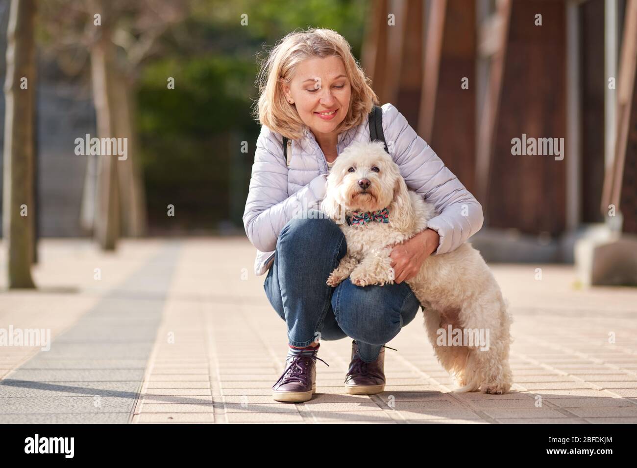 Mature woman walking with fluffy white dog in summer city Stock Photo ...
