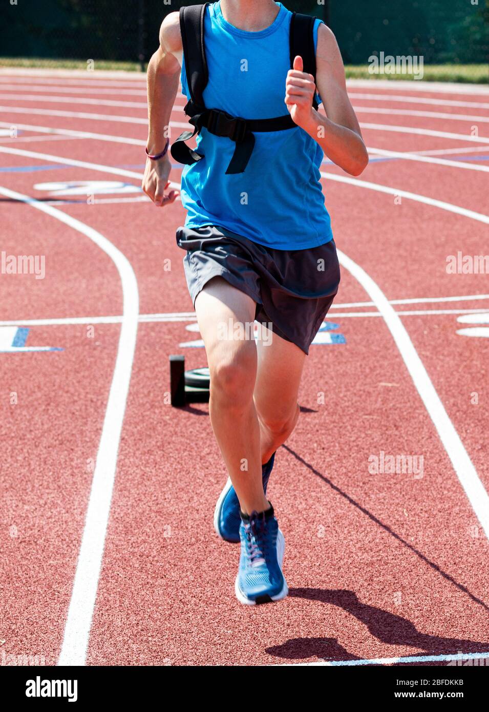 Close up of front view of a runner dragging a sled with weights behind ...