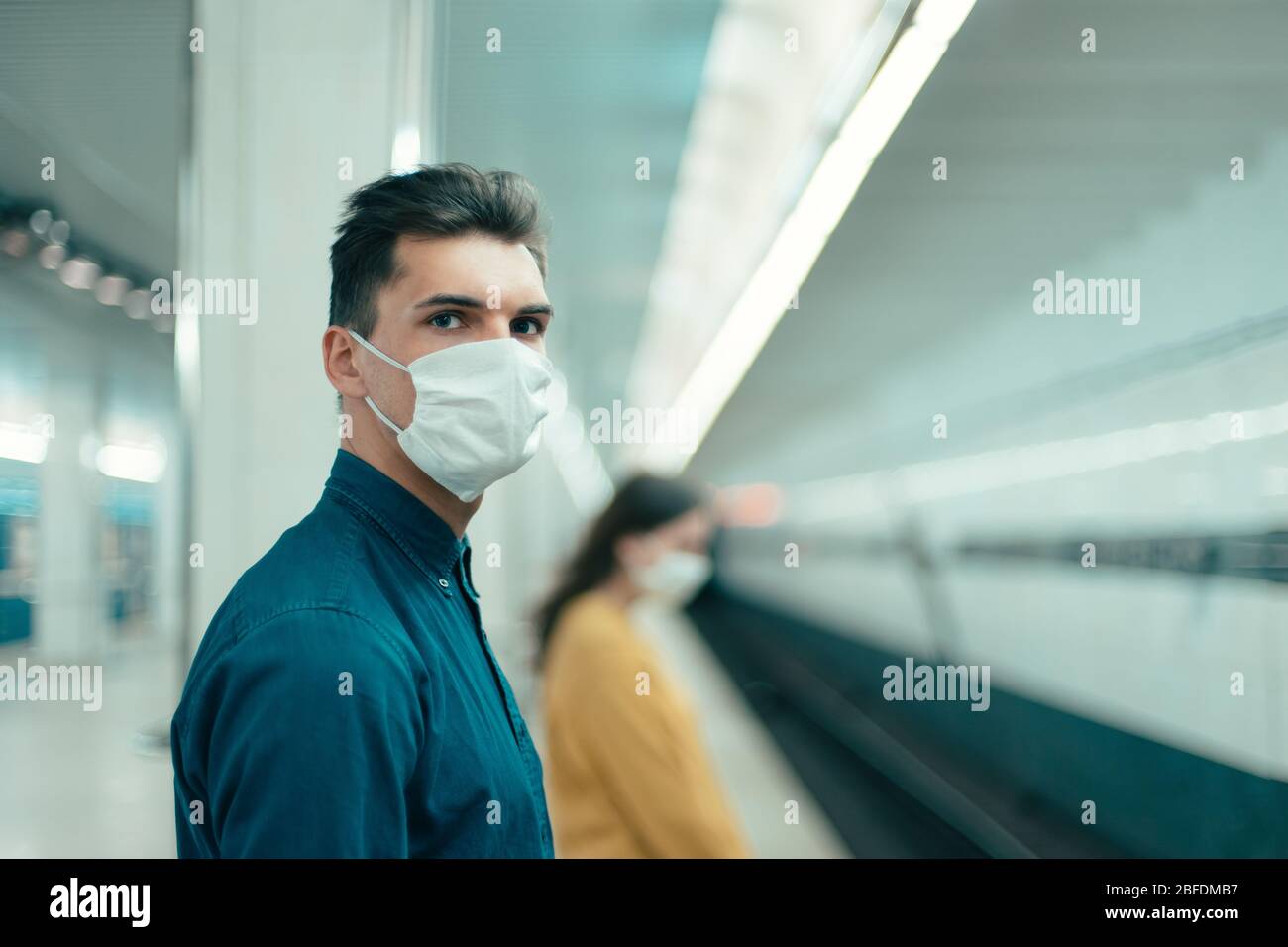 passengers in protective masks standing at a metro station at a safe ...