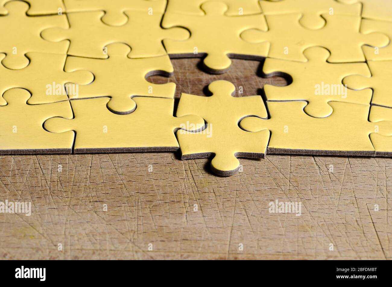 white jigsaw/puzzle with one piece at wrong position, over black wooden ...