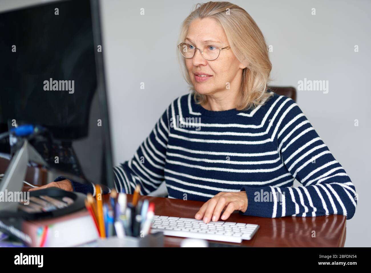 mature middle aged in glasses using laptop typing email working at home ...