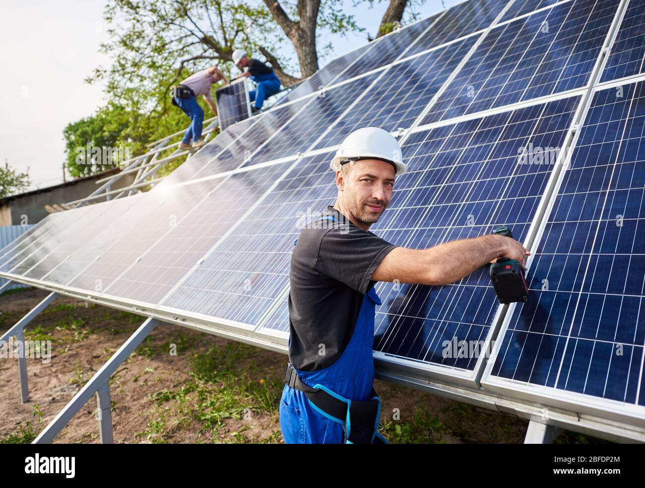 Smiling engineer technician mounting solar photo voltaic panel using ...