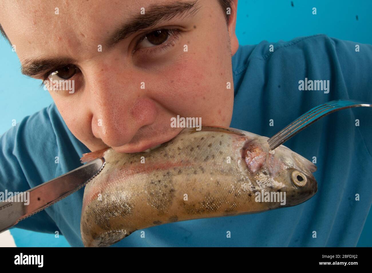 Young man with a large fresh fish in his mouth Stock Photo - Alamy