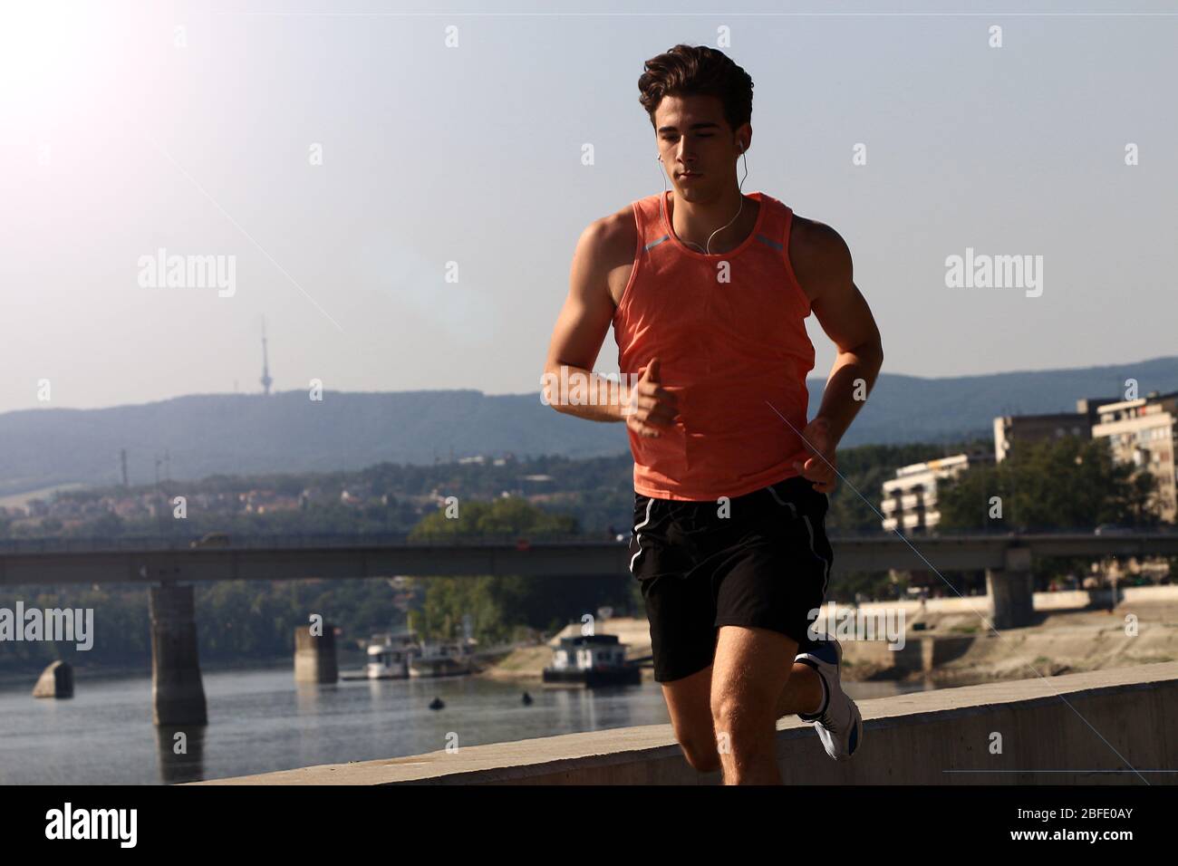 Young male athlete running by the Danube river at quay in Novi Sad ...
