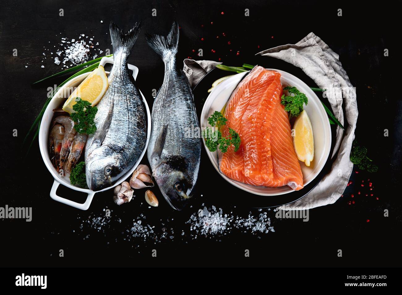 Fresh raw fish and seafood on black background. Top view, flat lay ...