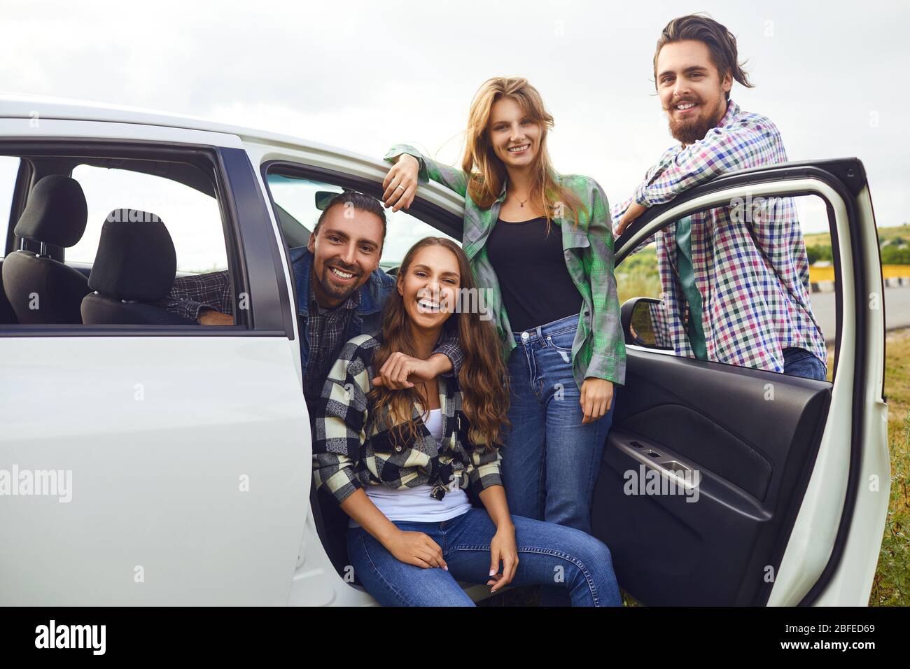 Group of people standing next travel in the car on road Stock Photo - Alamy