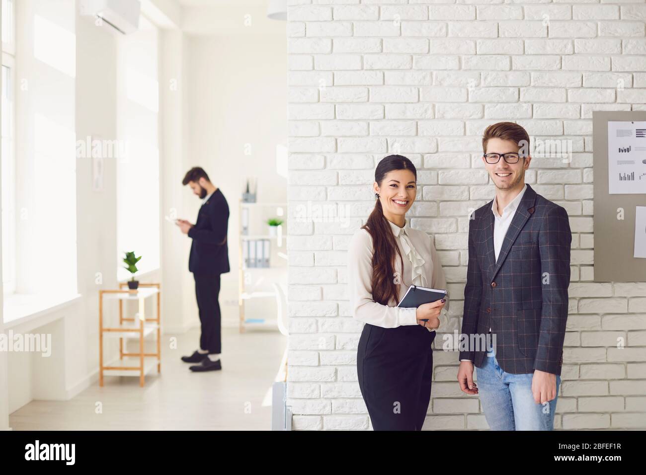 Business people stand smiling look in a white office Stock Photo - Alamy