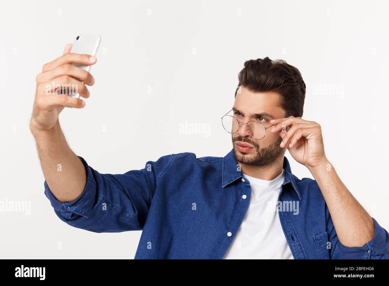 Portrait of an attractive young man taking a selfie while standing and ...